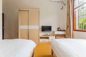 Quarto de hotel com duas camas, televisão, escrivaninha e guarda-roupa.
