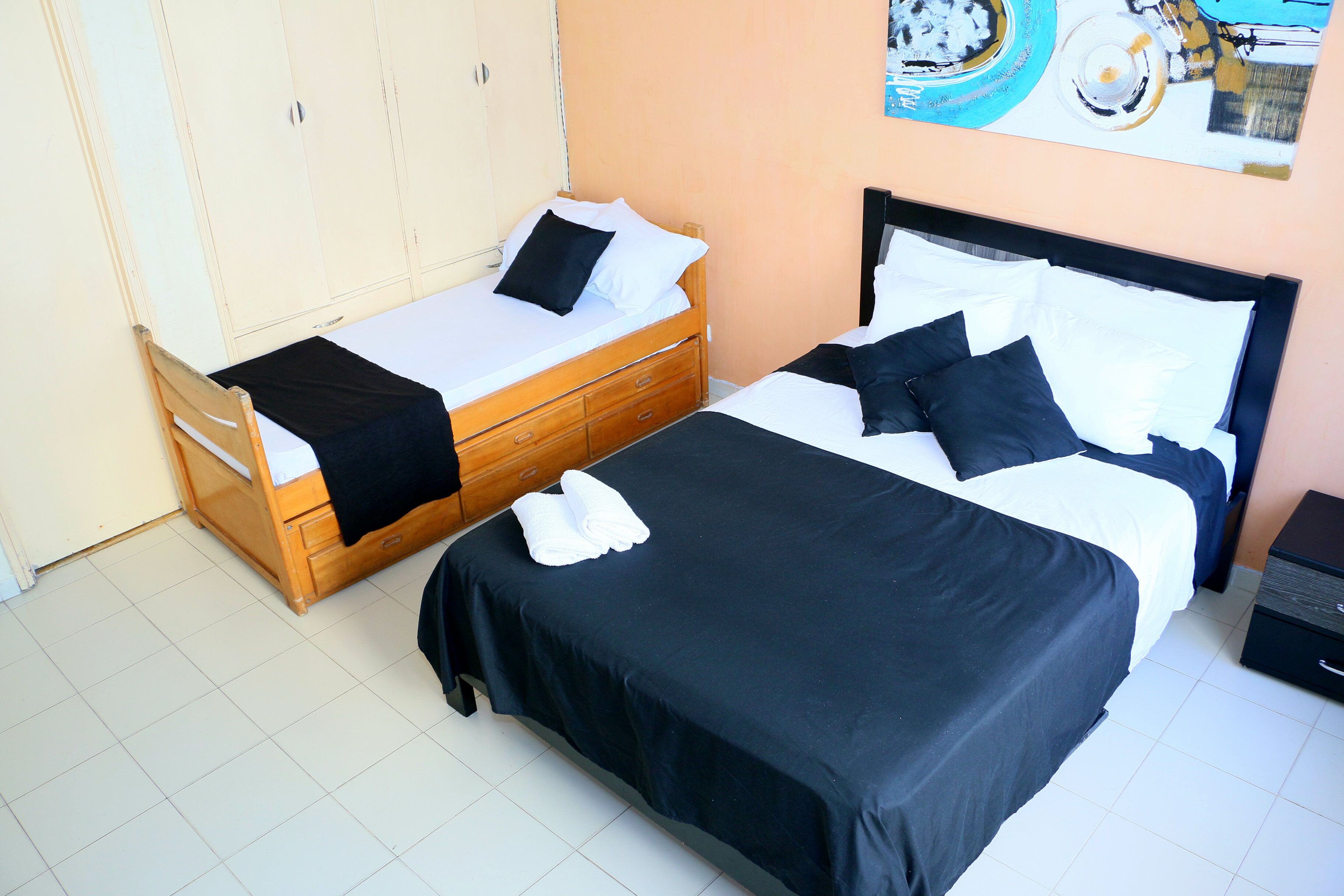Quarto com duas camas, um guarda-roupa e um quadro na parede.
