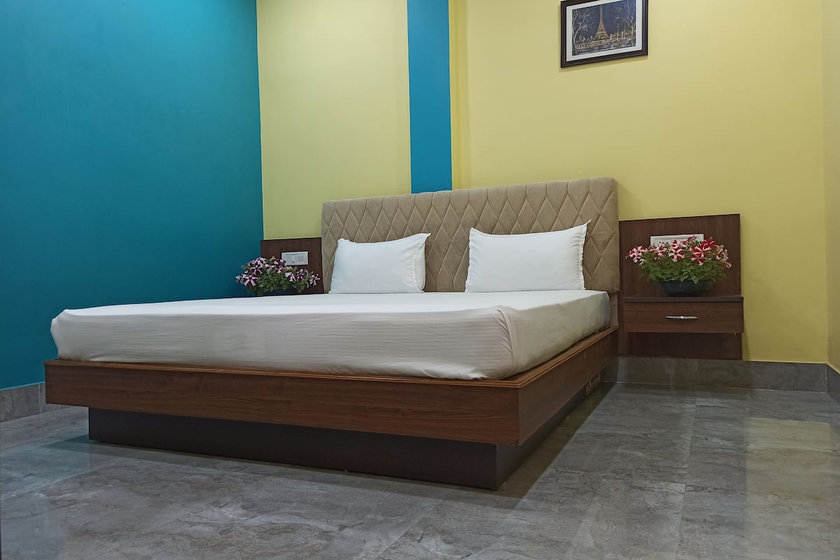 Quarto moderno com uma cama grande, cabeceira de madeira, duas mesas de cabeceira com vasos de flores e um quadro na parede.