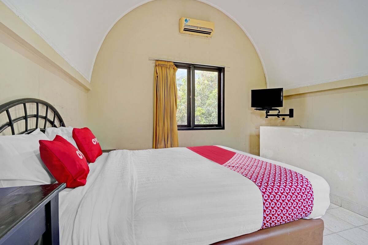 Quarto de hotel com cama, televisão e ar condicionado.