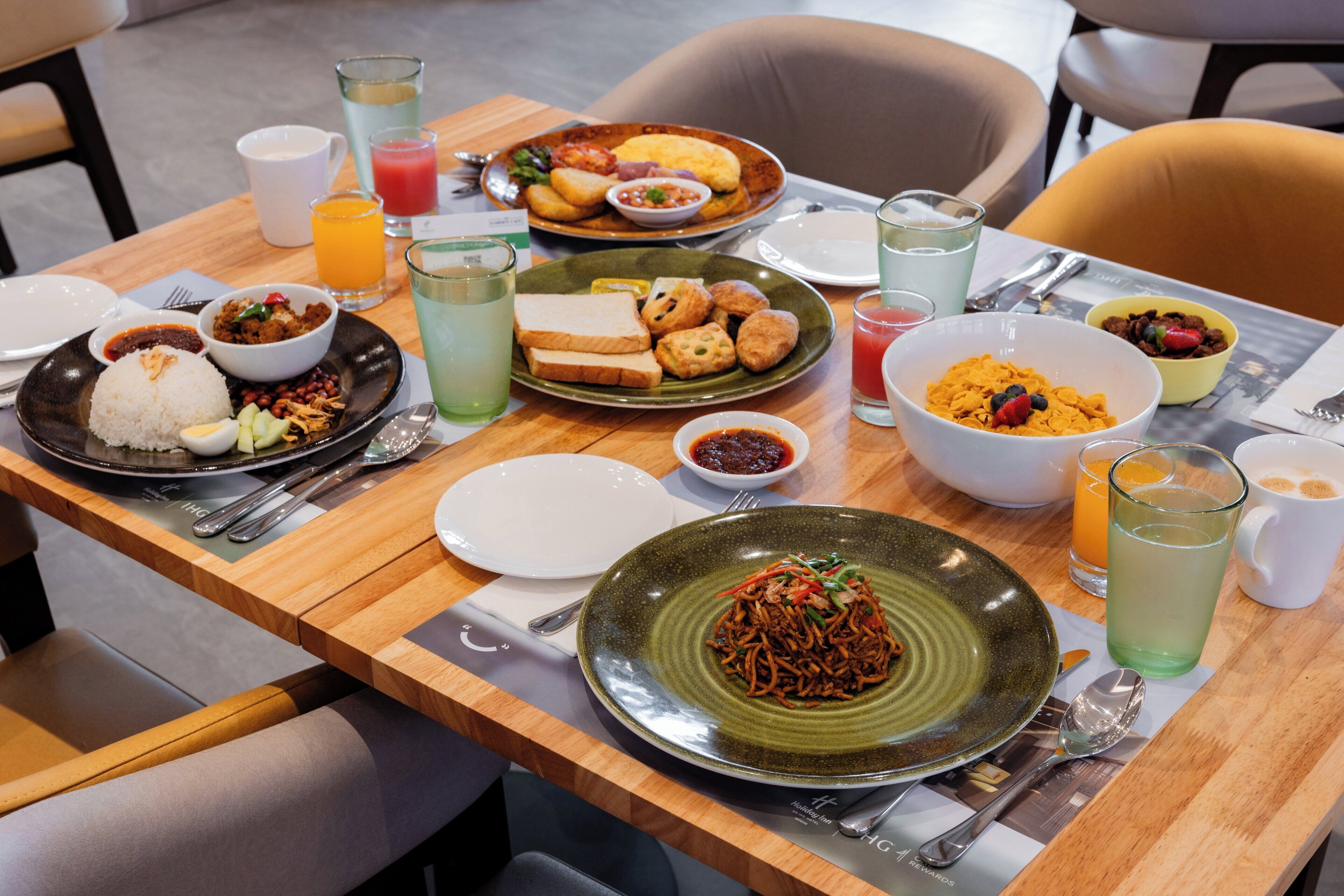 Mesa de jantar posta com diversos pratos, incluindo arroz, macarrão e pão, além de vários copos com bebidas.