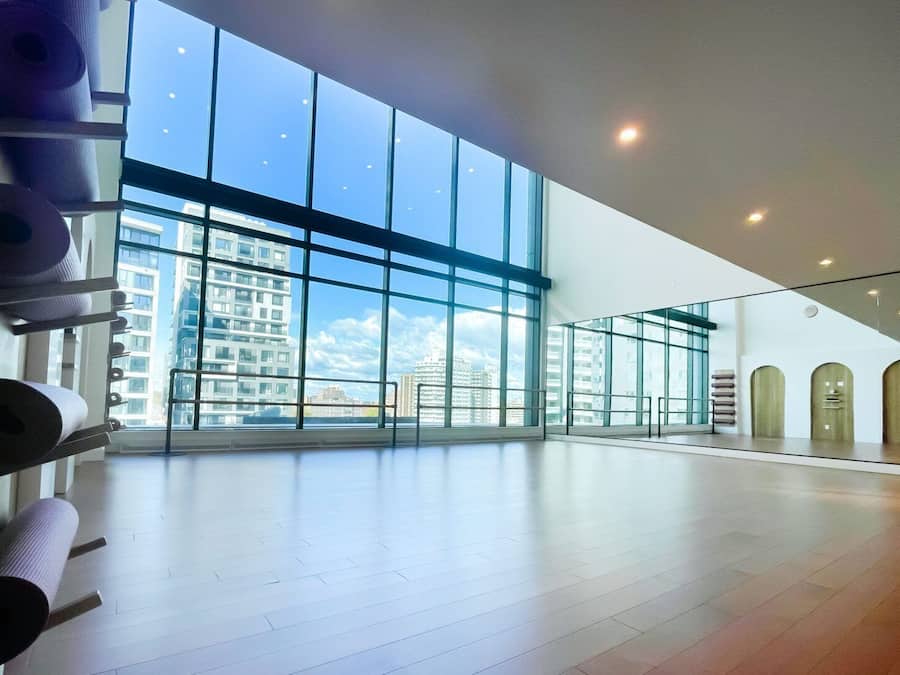 Um interior espaçoso com grandes janelas, piso de madeira e um porta-toalhas fixado na parede.