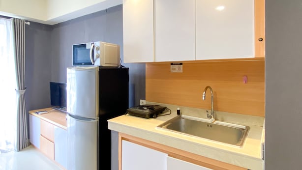 Uma cozinha compacta com micro-ondas, geladeira, pia e armários.