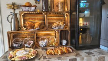 Buffet de café da manhã com diversos pães, frios, queijos e frios.