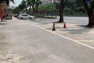 Rua com calçada, árvores e carros estacionados.