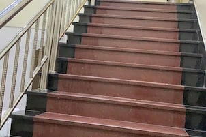 Um lance de escadas com corrimão à esquerda e borda preta à direita.