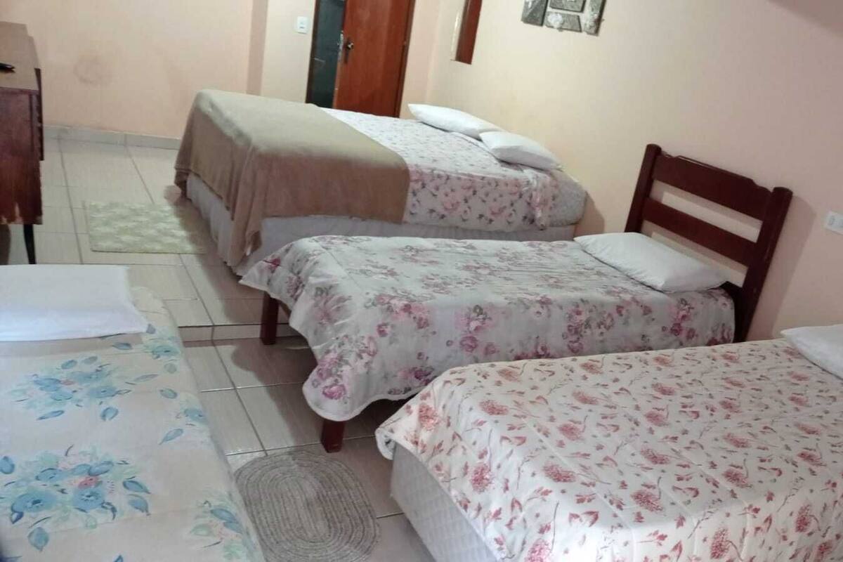 Quarto com duas camas de solteiro, cabeceira de madeira, uma mesinha e uma cadeira.
