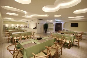 Uma ampla área de refeições com várias mesas e cadeiras, um balcão central e um design de teto moderno.