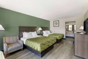 Quarto de hotel com duas camas, uma escrivaninha, uma cadeira e uma televisão.