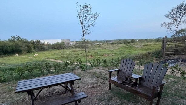 Uma área externa com mesa de piquenique e duas cadeiras Adirondack.