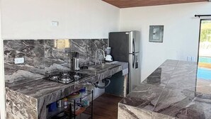 Uma cozinha moderna com bancadas de mármore, teto de madeira e fogão embutido.