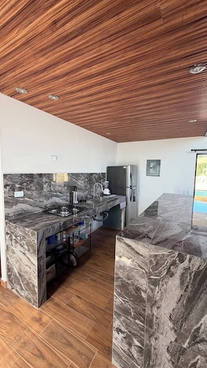 Uma cozinha moderna com bancadas de mármore, teto de madeira e fogão embutido.