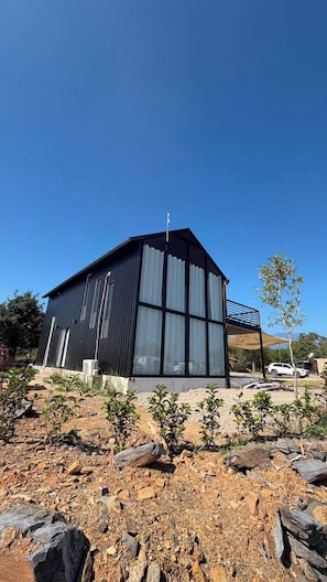 Um edifício moderno com fachada escura, grandes janelas e telhado inclinado.