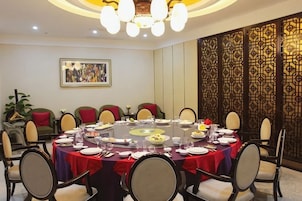Uma sala de conferências com uma mesa redonda, cadeiras e um candelabro.