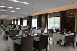 Uma sala de conferências com várias mesas e cadeiras, grandes janelas e vista para o exterior.