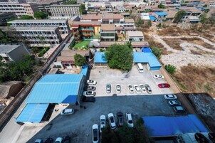 Vista aérea de um estacionamento com vários carros, cercado por edifícios com telhados azuis.