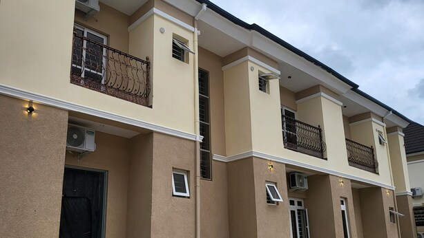 Um edifício residencial com vários andares, varandas, aparelhos de ar condicionado e uma área de entrada com azulejos.