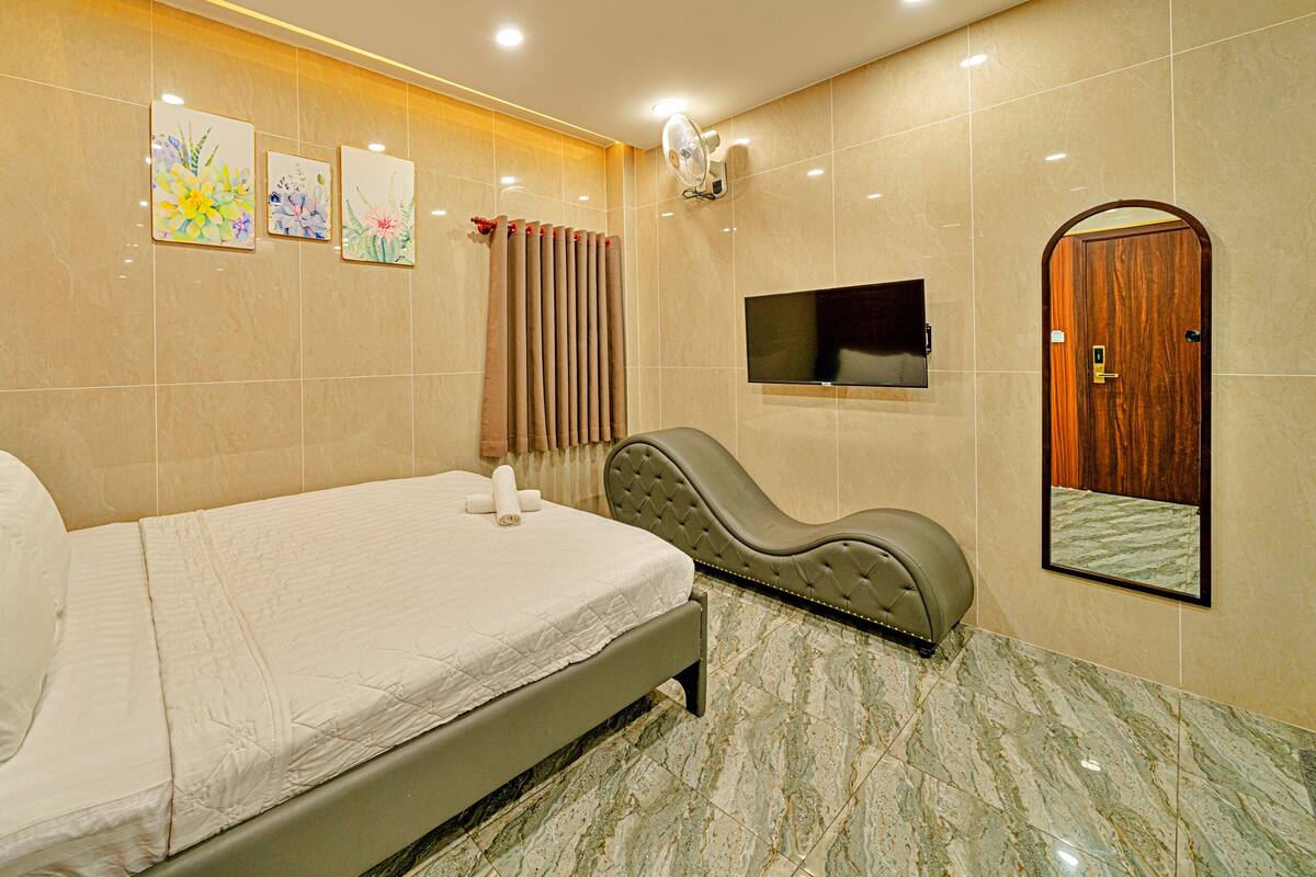 Quarto de hotel com cama, televisão de tela plana, espelho e obras de arte na parede.