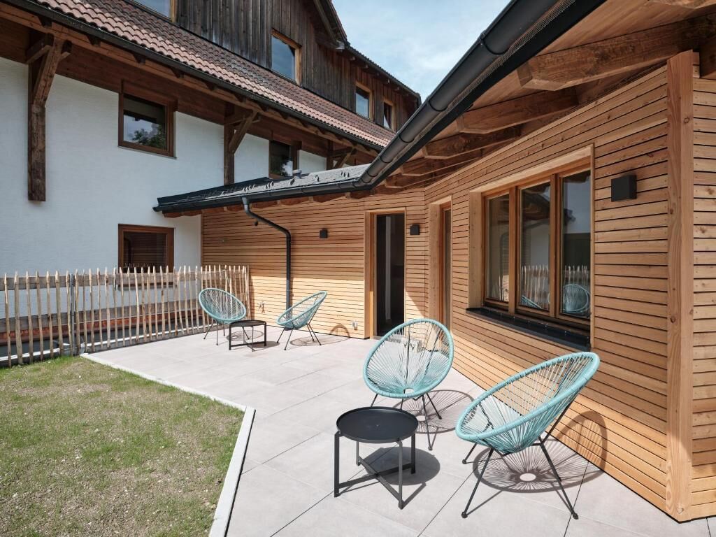 Uma casa de madeira com um espaço de pátio que inclui duas cadeiras e uma mesa.