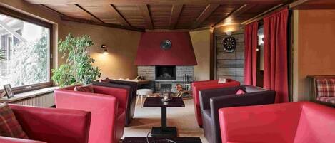Uma sala de estar aconchegante com sofás vermelhos, lareira e vista para o exterior.