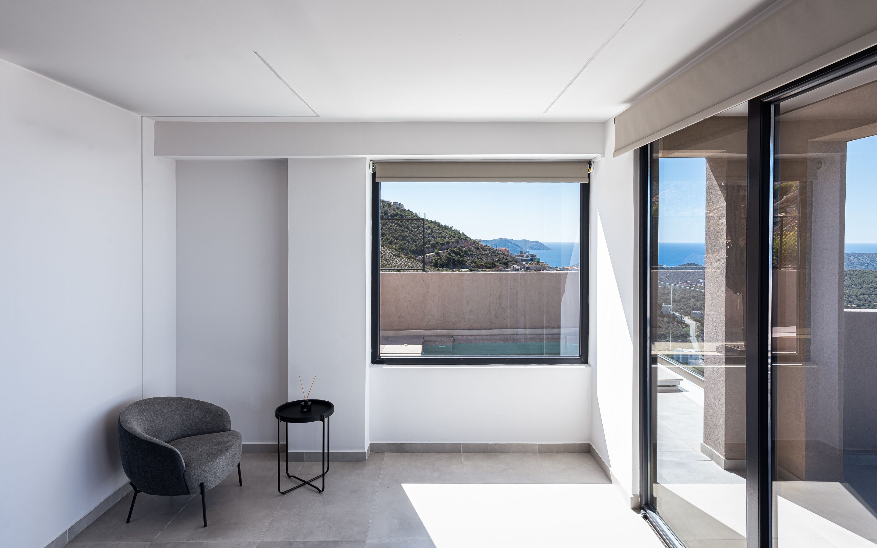 Quarto moderno e minimalista com uma grande janela e vista para a paisagem costeira.
