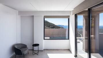 Quarto moderno e minimalista com uma grande janela e vista para a paisagem costeira.