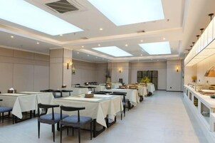Uma sala de jantar espaçosa, com várias mesas e cadeiras, tetos altos com claraboias e um design de interiores moderno.