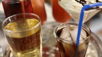 Uma bandeja com diversas bebidas, incluindo chá gelado, limonada e um coquetel com canudo azul.