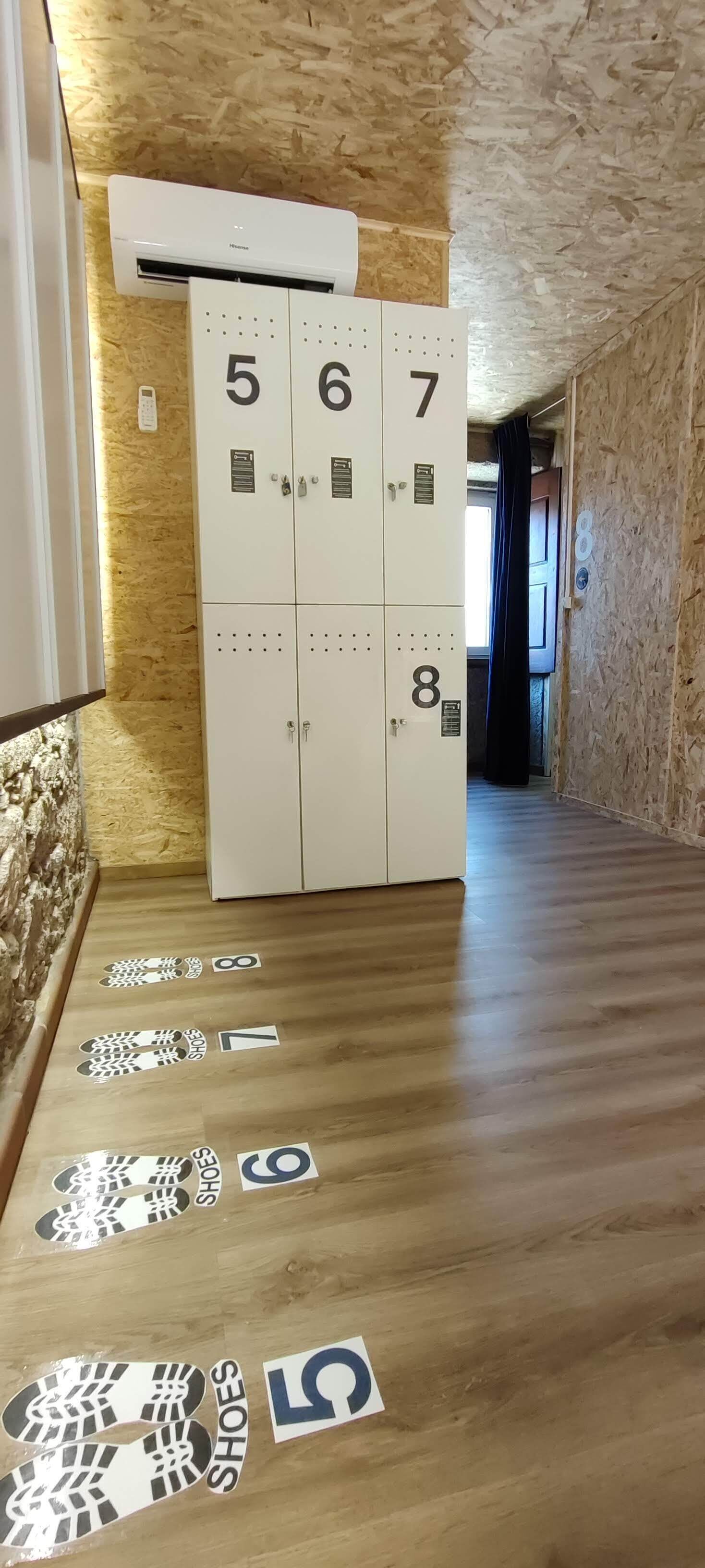 Um corredor com armários numerados de 5 a 8, paredes e chão de madeira.
