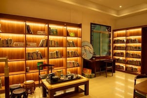Uma biblioteca com estantes de livros, uma mesa repleta de livros e uma cadeira de estilo tradicional.