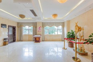 Um hall de hotel espaçoso com piso de mármore, balcão de recepção e uma grande janela com vista para o exterior.