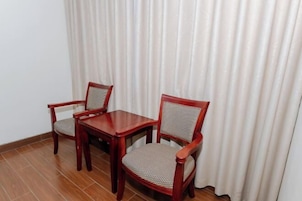 Um quarto pequeno com uma mesa de madeira e duas cadeiras.