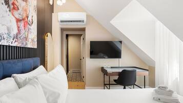 Quarto de hotel moderno com cama, escrivaninha, televisão e uma grande janela.