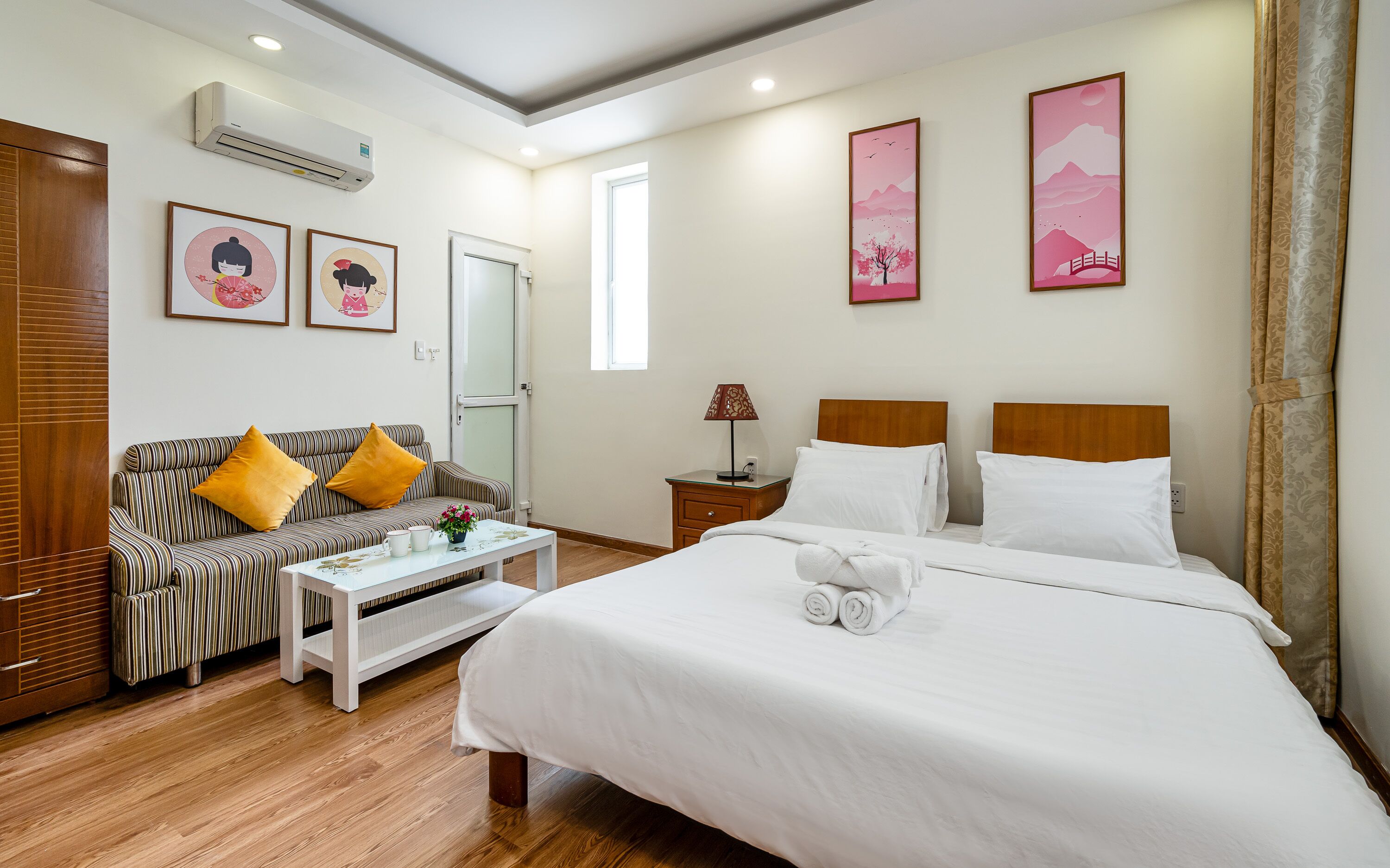 Quarto de hotel com uma cama, um sofá, uma mesinha e obras de arte nas paredes.
