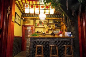 Uma área de bar com banquetas, prateleiras com garrafas e um lustre.