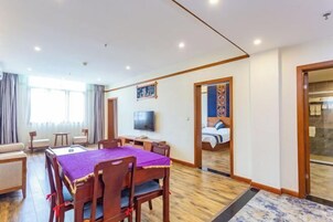 Quarto de hotel com área de refeições, televisão, cama e vista para o exterior.