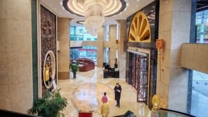 Um lobby espaçoso com teto alto, um lustre central e uma área de estar.