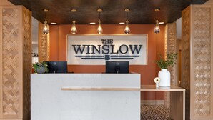 Balcão de recepção com uma placa que diz 'THE WINSLOW' e dois monitores de computador.
