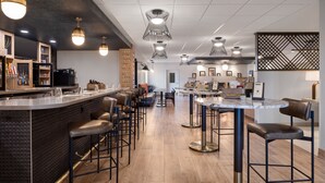 Uma área de bar moderna com balcão, banquetas e iluminação pendente.