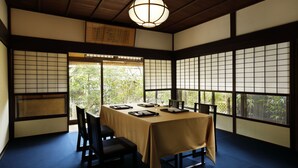 Um quarto japonês tradicional com tatames, uma mesa baixa com toalha de mesa bege e portas deslizantes shoji.