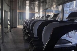Fileira de bicicletas ergométricas num espaço com amplas janelas.