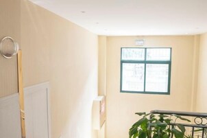 Quarto com janela, radiador e planta.