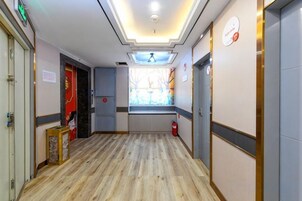 Corredor de hotel com piso de madeira, um extintor de incêndio e uma janela com vista.