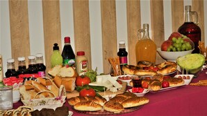 Uma mesa com diversos alimentos e bebidas, incluindo pão, queijo, frutas e acompanhamentos.