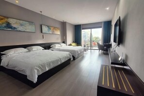 Quarto de hotel com duas camas, uma mesa de escritório, televisão e varanda com vista.