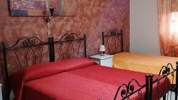 Quarto com cama, mesa de cabeceira, abajur e um quadro na parede.