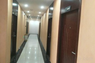 Um corredor com portas em ambos os lados, uma placa sobre uma delas e piso cerâmico.