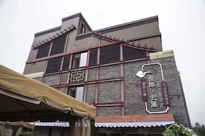 Um edifício com estilo arquitetônico tradicional, destacando uma entrada imponente com toldo decorativo e uma placa com texto.