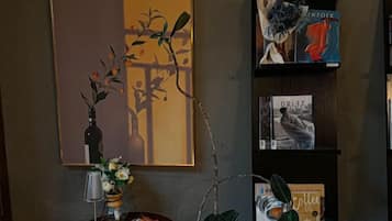 Quarto com estante, uma obra de arte emoldurada e uma mesinha com abajur e livros.