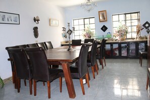 Uma sala de jantar com mesa e cadeiras de madeira, um candelabro e obras de arte nas paredes.